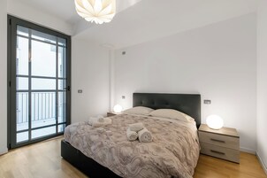 Quarto com uma cama grande, abajures, janela com vista e luminária moderna.