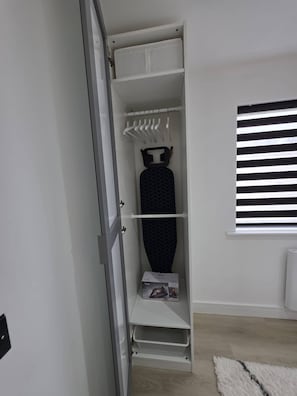 Um guarda-roupa branco com prateleiras, espaço para pendurar roupas e um sapateiro.