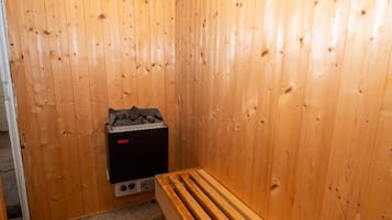Uma sala de sauna com paredes de madeira, um banco e um equipamento de sauna HELO.