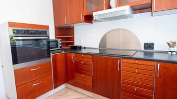 Cozinha com armários de madeira, forno embutido, micro-ondas e exaustor.