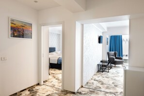Quarto de hotel com cama, uma cadeira, uma mesa e um quadro na parede.