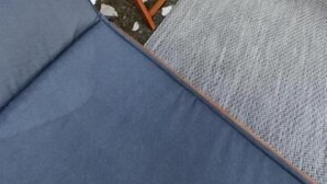 Uma pequena área externa com assentos, incluindo duas poltronas e uma mesa pequena, uma garrafa de bebida e um vaso com planta.
