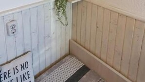 Um corredor com uma placa que diz 'Não há lugar como o LAR', uma frase emoldurada na parede e um tapete estampado no chão.
