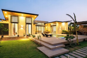 Uma casa moderna com piscina, área de estar externa e gramado bem cuidado.