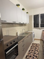 Uma cozinha moderna com eletrodomésticos de aço inoxidável, forno embutido, pia e janela com vista.