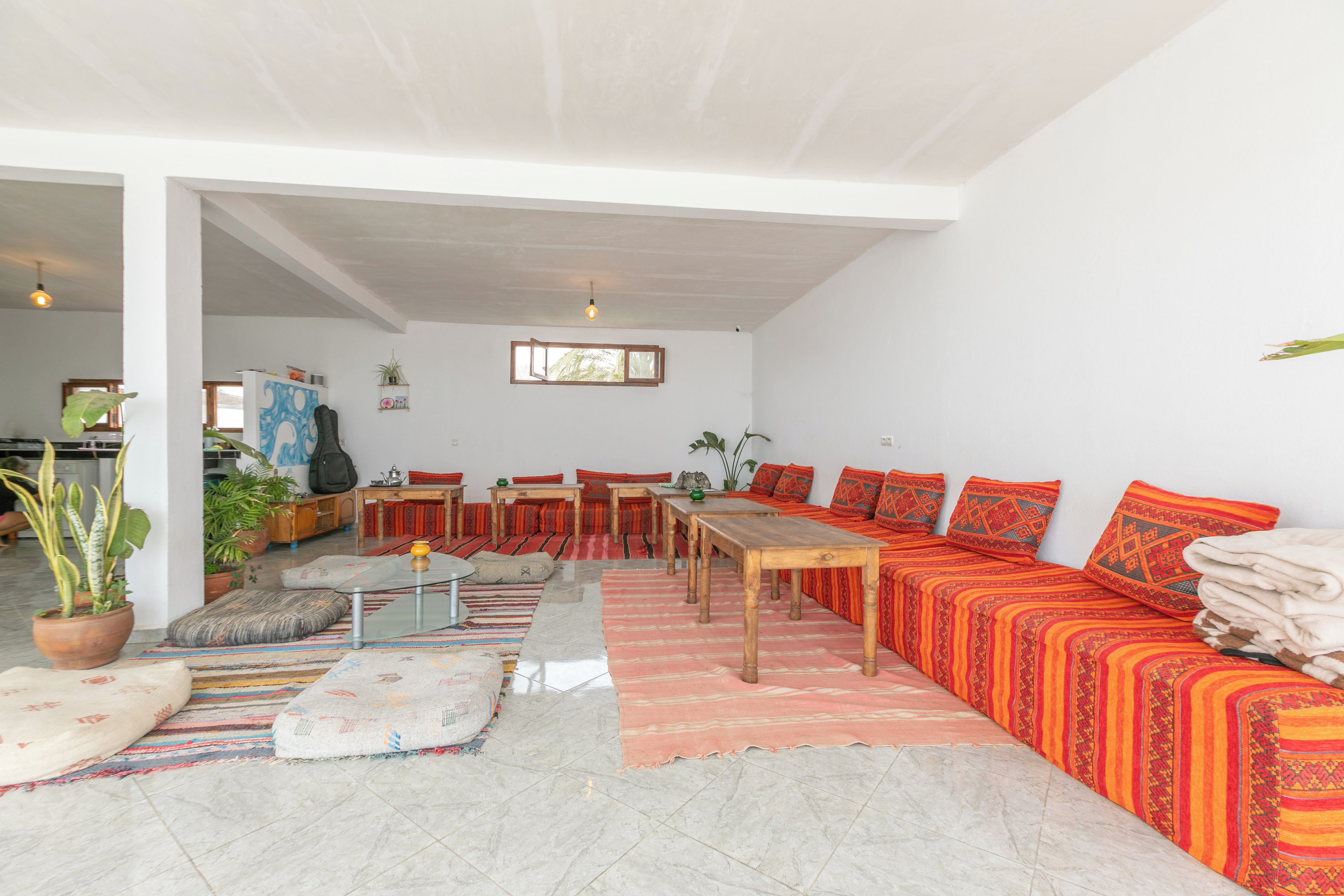 Uma sala de estar ampla com sofás, uma mesa de jantar e uma cozinha ao fundo.