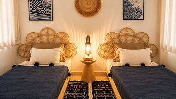 Quarto com duas camas, uma lâmpada central e obras de arte nas paredes.