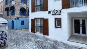Um edifício com uma placa que diz 'amber butik hotel' e uma rua de paralelepípedos.