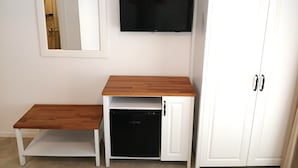 Uma cozinha compacta com bancada de madeira, lava-louças preta e armário branco com duas portas.