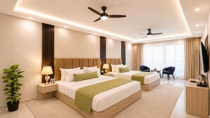 Quarto de hotel com duas camas, um ventilador de teto, uma televisão e um vaso de plantas.