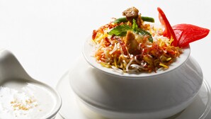 Uma tigela de biryani acompanhada de iogurte.