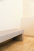 Canto de um quarto com um banco embutido na parede e piso ladrilhado.