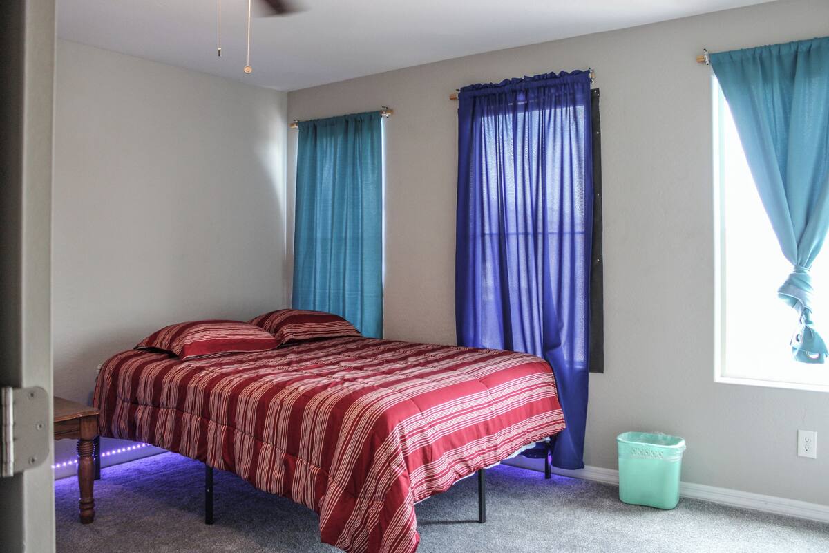 Quarto com cama, cortinas, janela e lixeira.