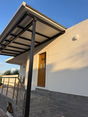 Um edifício com entrada coberta, porta com design decorativo e escadas que levam à entrada.
