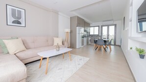 Uma sala de estar moderna com sofá, mesa de centro e um espaço de jantar com cadeiras e mesa.