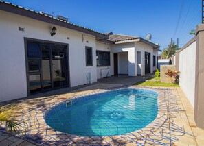 Um edifício residencial com piscina, antena parabólica e porta com painéis de vidro.