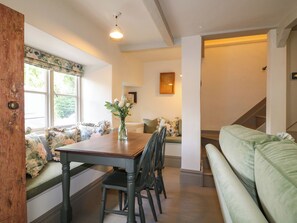 Uma sala de jantar com uma mesa de madeira, cadeiras e um vaso de flores.