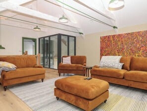 Uma sala de estar moderna com dois sofás, uma mesa de centro e uma pintura abstrata colorida na parede.