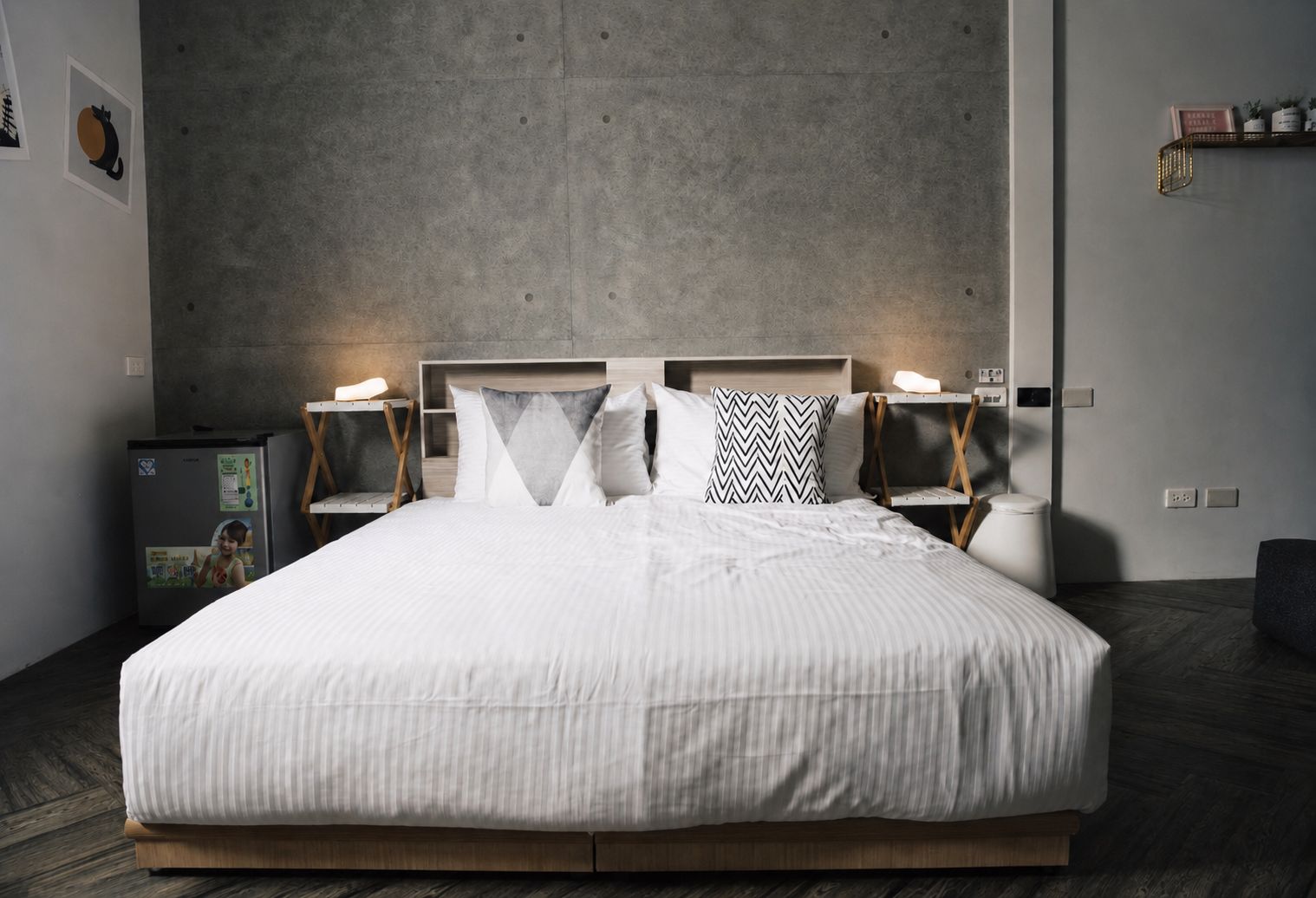 Quarto moderno com cama grande, mesas de cabeceira e prateleira na parede.