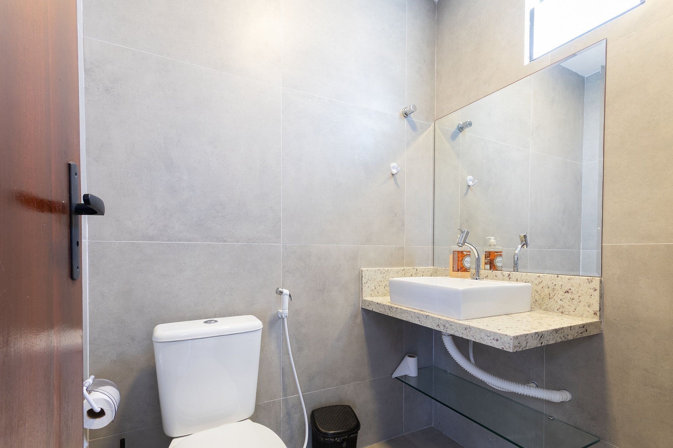 Uma casa de banho moderna com sanita, lavatório e chuveiro.