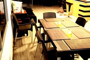 Uma área de refeições com uma mesa posta para dois, cadeiras e um abajur.
