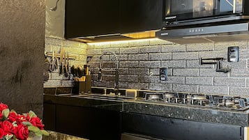 Uma cozinha moderna com armários pretos, fogão de aço inoxidável e micro-ondas.