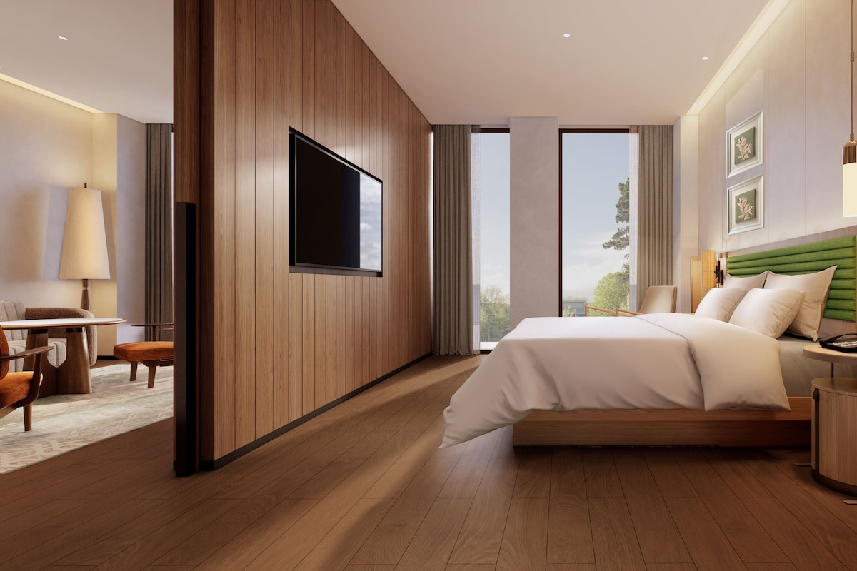 Quarto de hotel moderno com uma cama grande, uma escrivaninha e uma televisão.