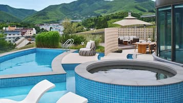 Piscina com banheira de hidromassagem, área de estar e vista para montanhas.