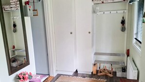 Quarto com um espelho grande, cómoda de madeira, tapete listrado, um banco e radiador.