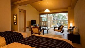 Quarto de hotel com duas camas, televisão, escrivaninha e cadeiras.