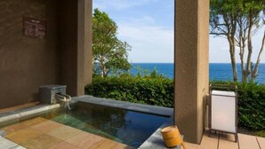 Área de spa com hidromassagem, deck de madeira e vista para o mar.