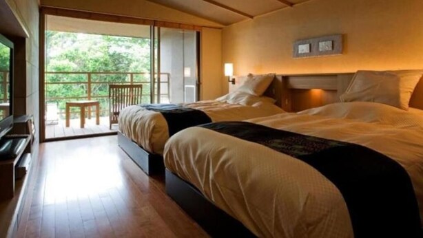 Quarto com cama, escrivaninha e vista para o exterior.