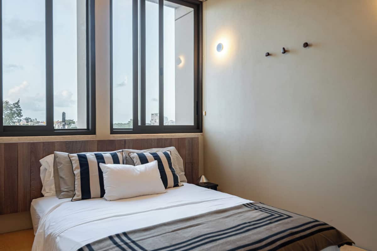 Quarto com uma cama grande, cabeceira de madeira, janela e luminária no teto.
