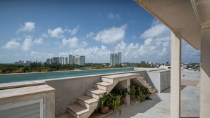 Piscina no terraço com vista para o horizonte urbano, degraus de concreto e plantas em vasos.