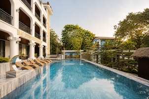 Uma piscina com um edifício com a inscrição 'BAIDINH ECO GARDEN' ao fundo.
