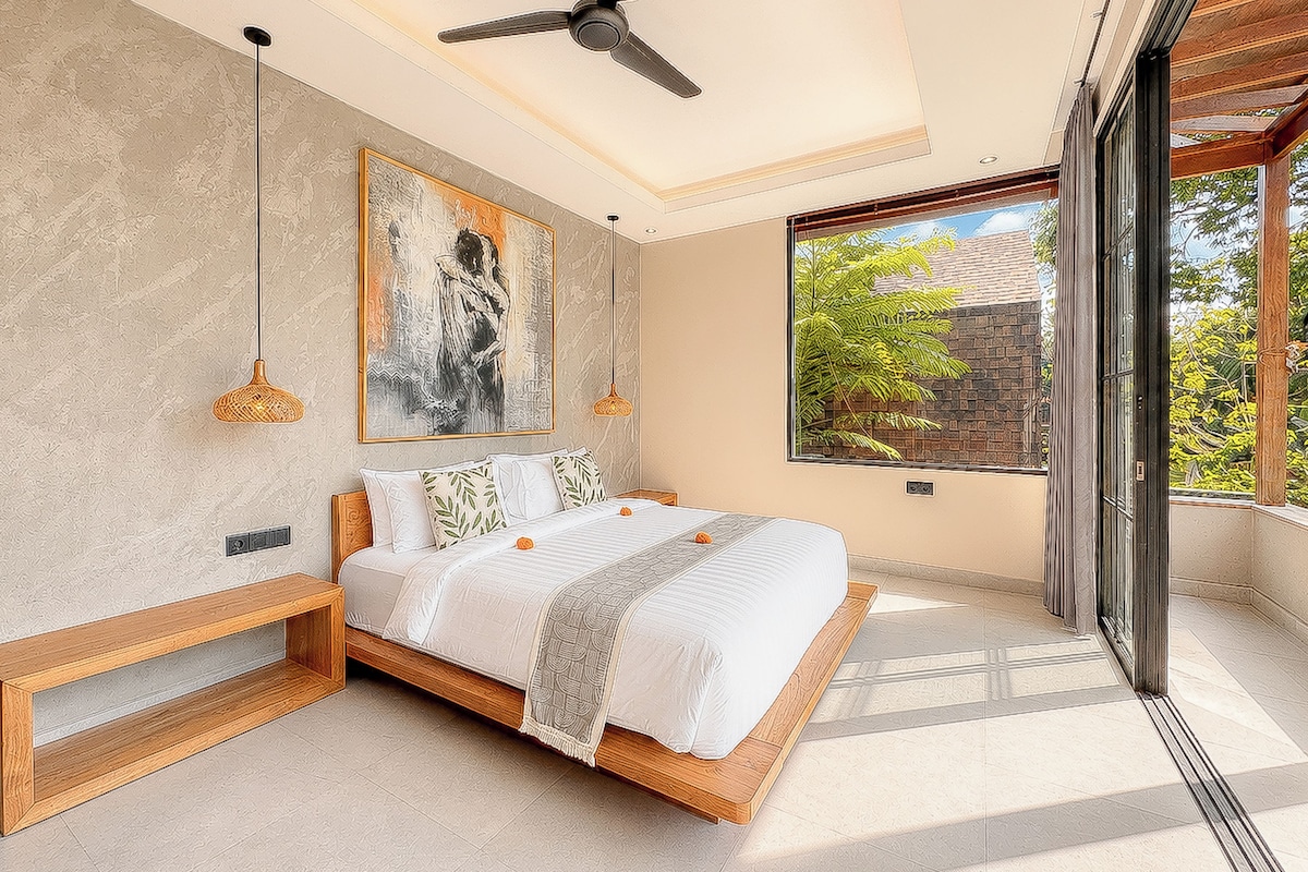 Quarto com cama, ventoinha no teto, uma janela grande e uma obra de arte na parede.