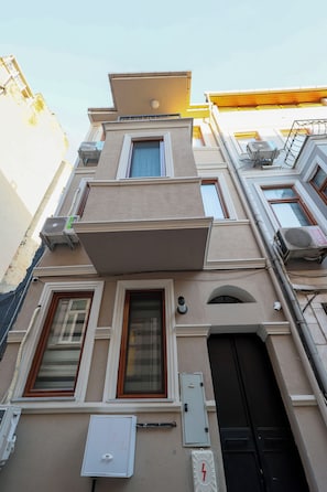Um edifício com vários andares, fachada plana, várias janelas e entrada central com porta preta.