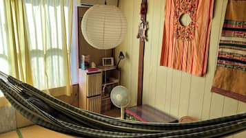 Quarto com rede, ventoinha, escrivaninha e computador, e parede decorada.