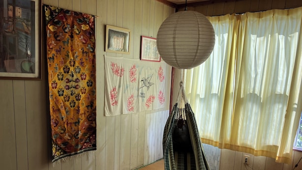 Um quarto com uma cadeira suspensa, tapeçaria estampada e uma janela com cortinas.