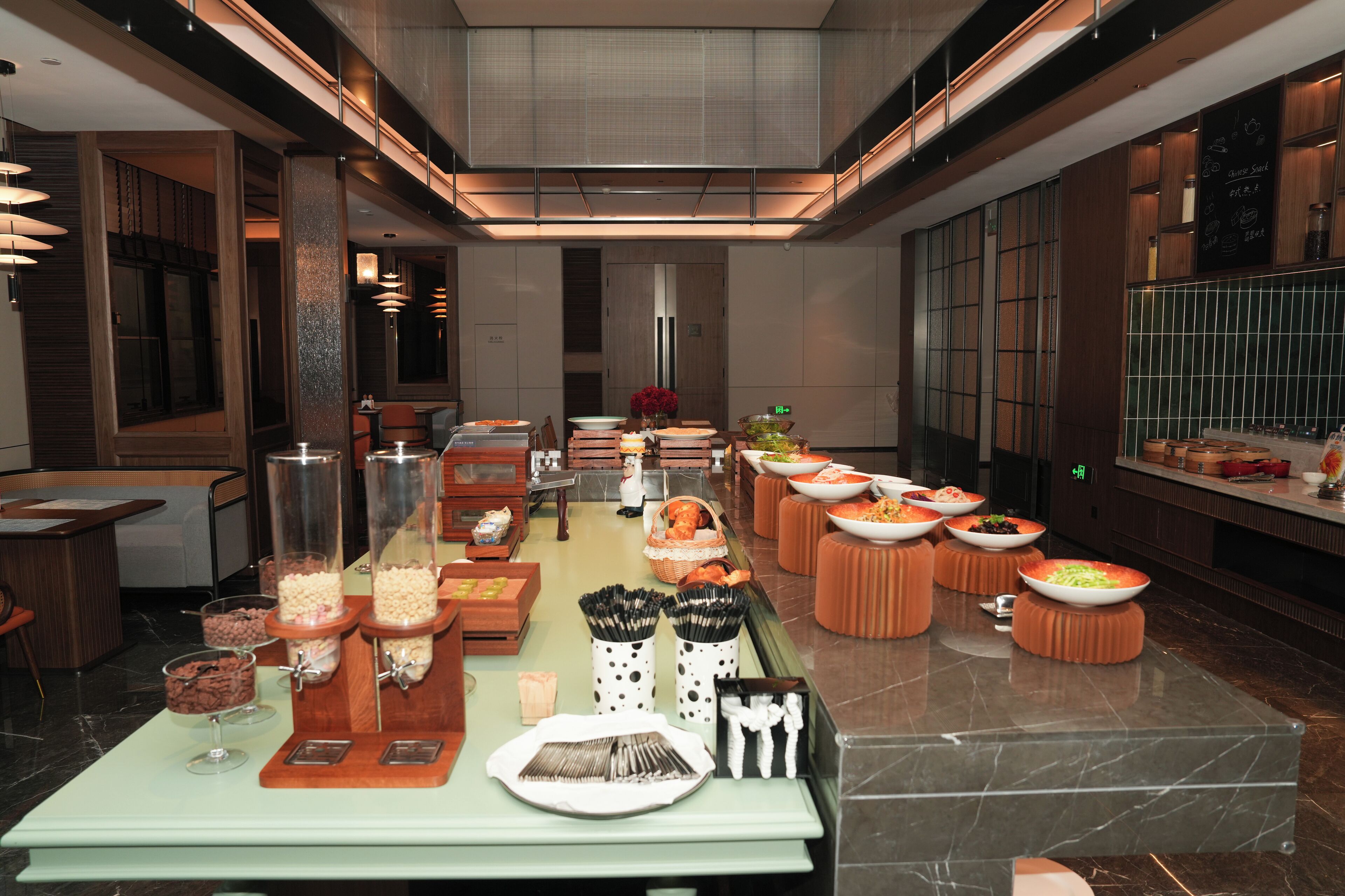 Buffet montado com diversos pontos de comida, área de recepção e design de interiores moderno.