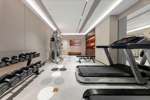 Academia com esteiras, halteres e máquina de musculação.