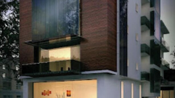 Um edifício moderno com fachada de tijolos em destaque, telhado plano e entrada visível com porta de vidro.