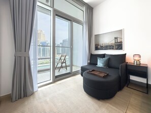 Uma sala de estar moderna com sofá, mesa lateral, bandeja e vista para a cidade através de grandes janelas.