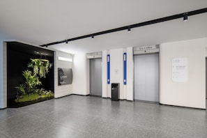 Área de elevador moderna com uma placa indicando 'ATCUR LIGHT' e um indicador de andar.