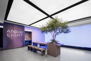 Um interior moderno com área de estar, um letreiro iluminado grande e uma planta em vaso.