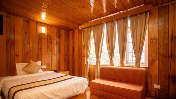Quarto de madeira com uma cama, um sofá e uma janela com cortinas.