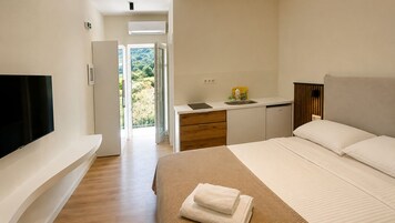 Quarto de hotel moderno com uma cama, uma escrivaninha, uma televisão e vista para o exterior.