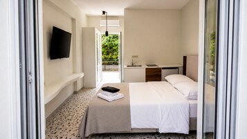 Quarto com cama, televisão, escrivaninha e janela.