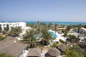 Um resort com piscina, palmeiras e vista para a praia.