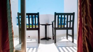 Uma varanda com duas cadeiras de madeira e uma mesa pequena, com vista desobstruída para o céu.